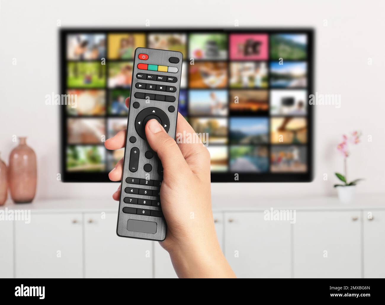 Streaming video services. Woman using remote control to change channels ...