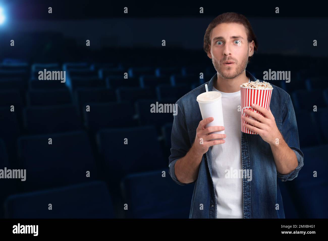 Emotional man with popcorn and beverage in cinema, space for text Stock ...