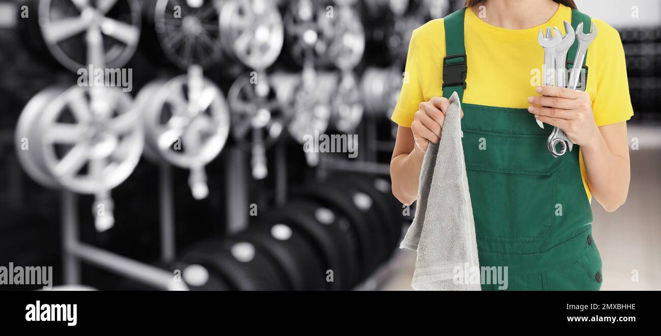 Professional mechanic with wrenches and rag at tire shop, closeup ...