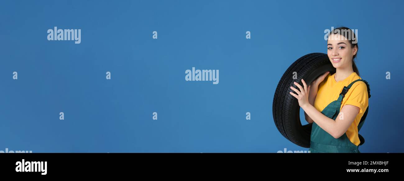 Seller in uniform with car tire on blue background, space for text ...