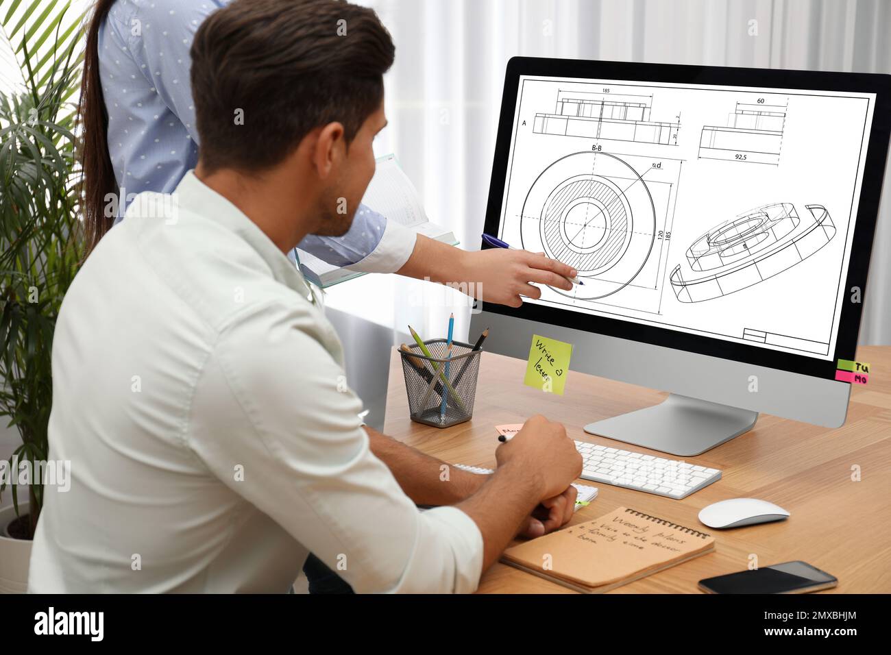 Colleagues working with technical drawing on computer in office Stock ...