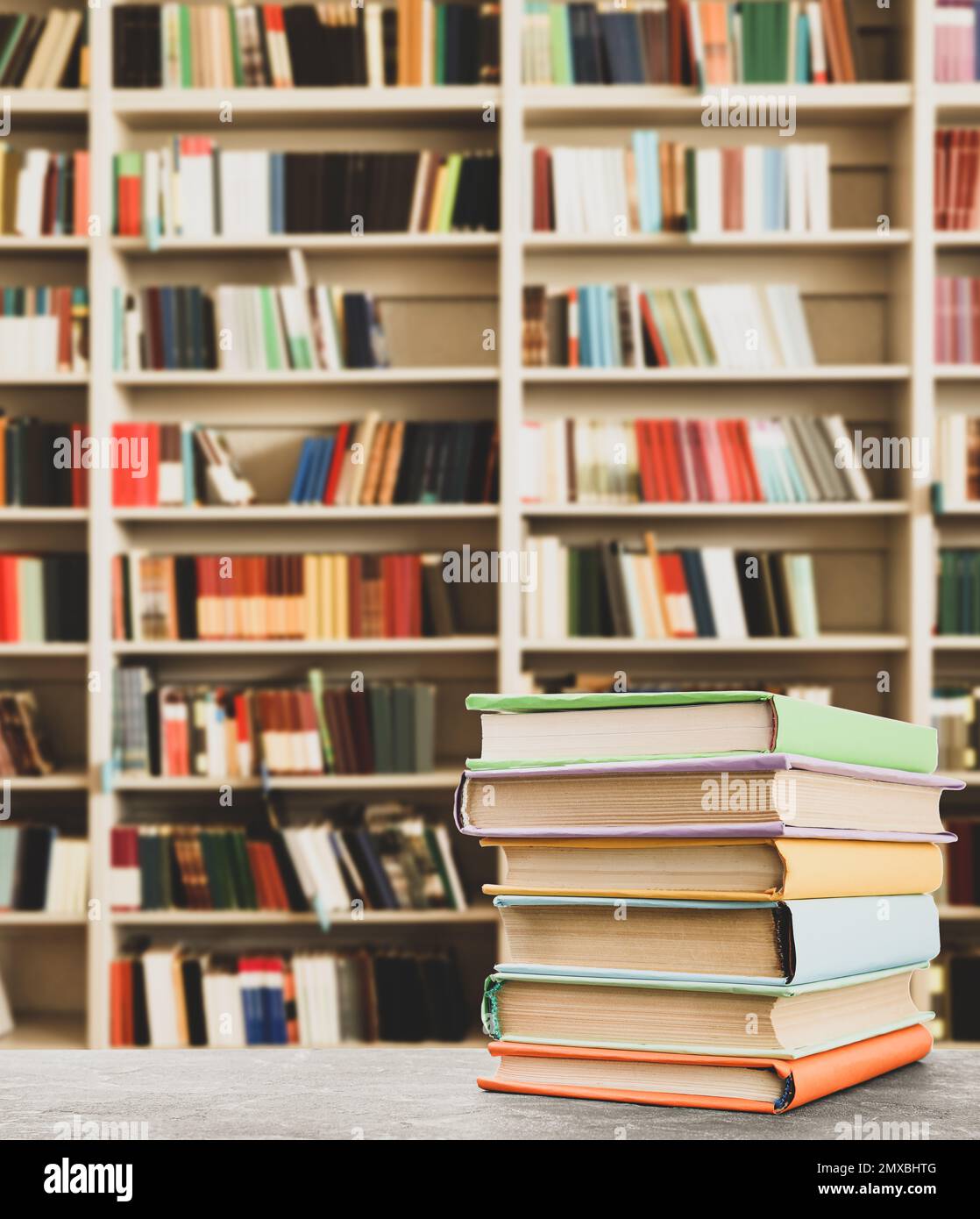 Stack of colorful books on table in library, space for text Stock Photo ...