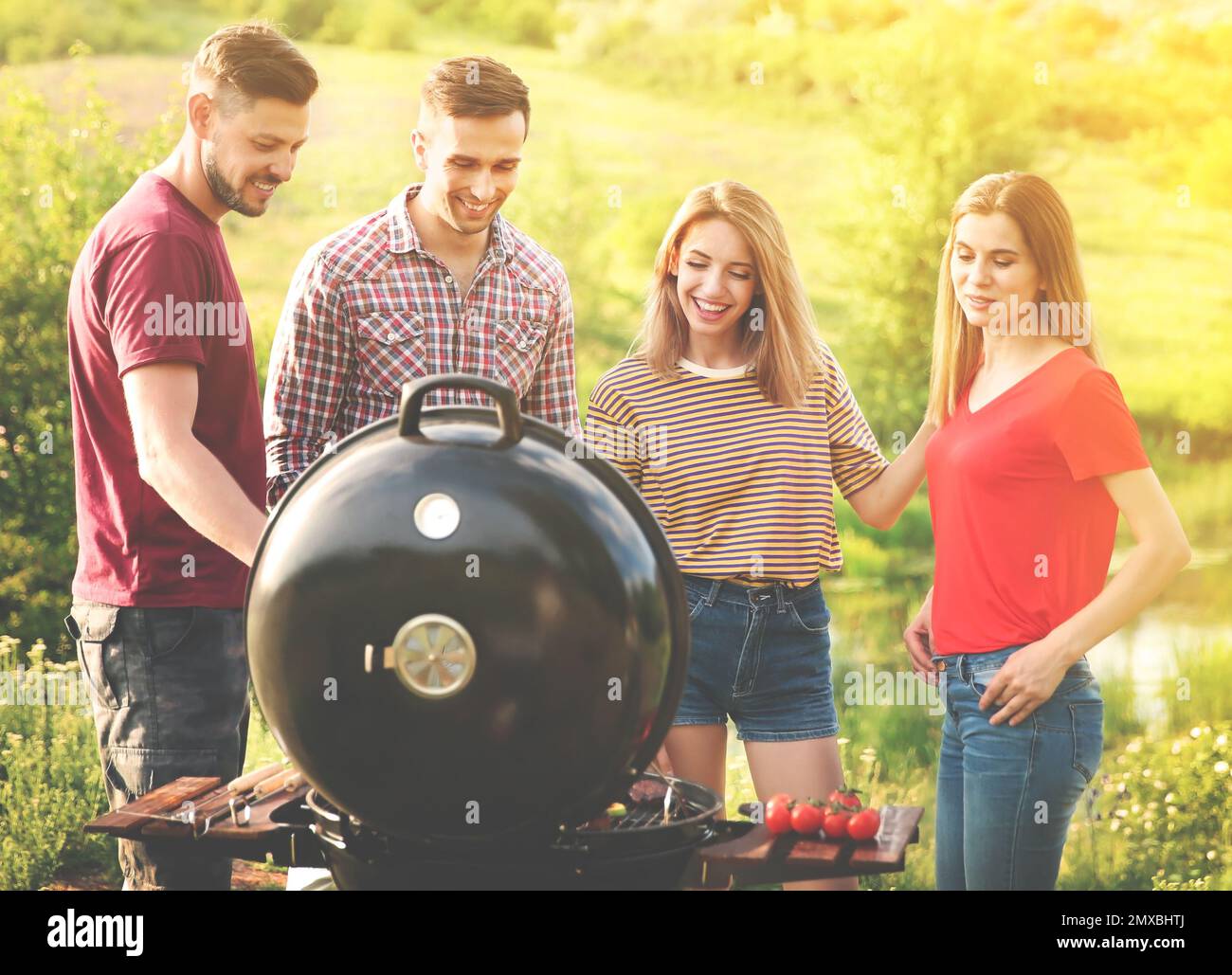 Young people having barbecue in wilderness on sunny day Stock Photo - Alamy