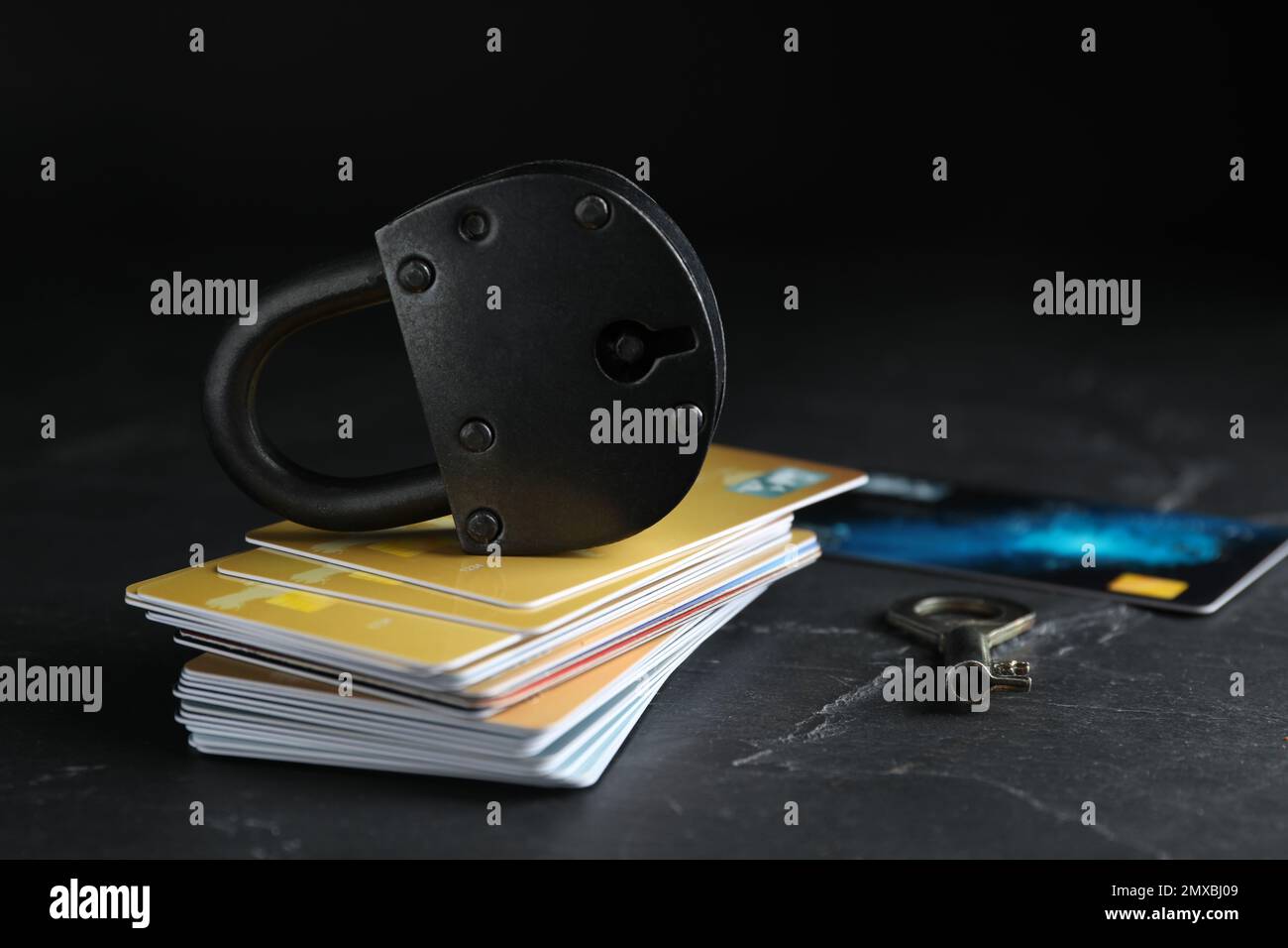 Credit cards, padlock and key on black slate table. Protection from ...