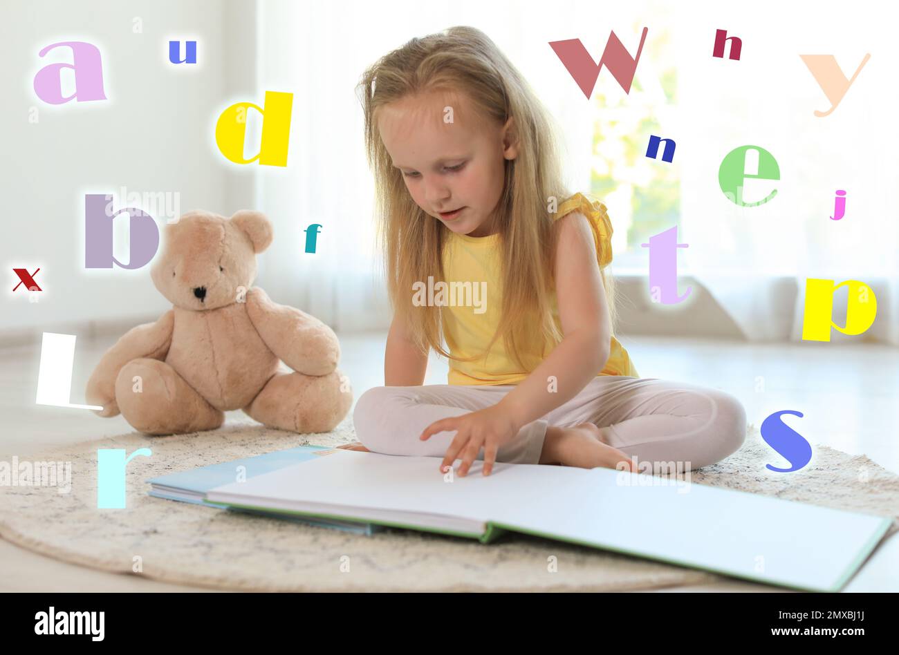 Pretty little girl reading book on floor in room Stock Photo - Alamy