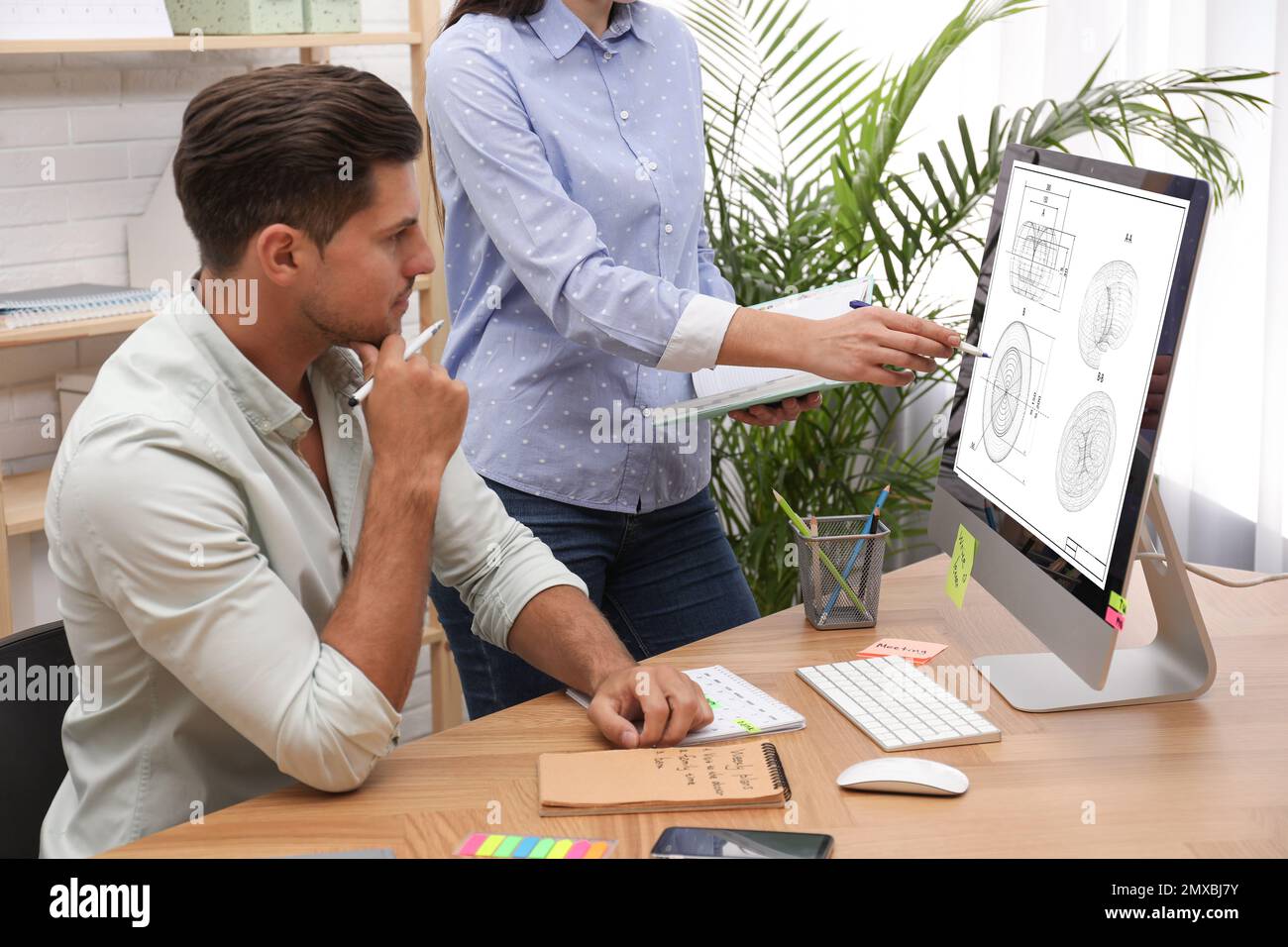 Colleagues working with technical drawing on computer in office Stock ...