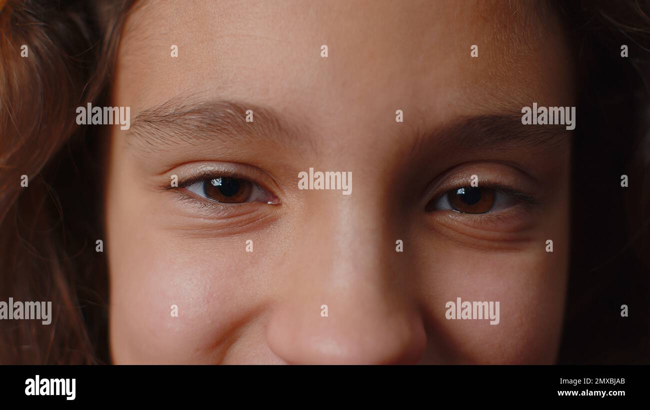 Extreme close-up macro portrait of smiling girl face. Teen beautiful kid's eyes, looking at ...