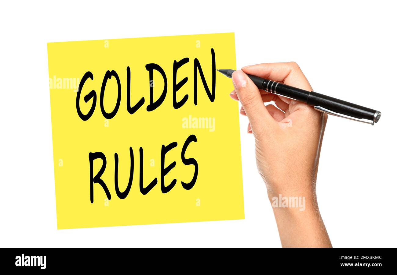 Young woman writing phrase GOLDEN RULES on yellow note against white ...