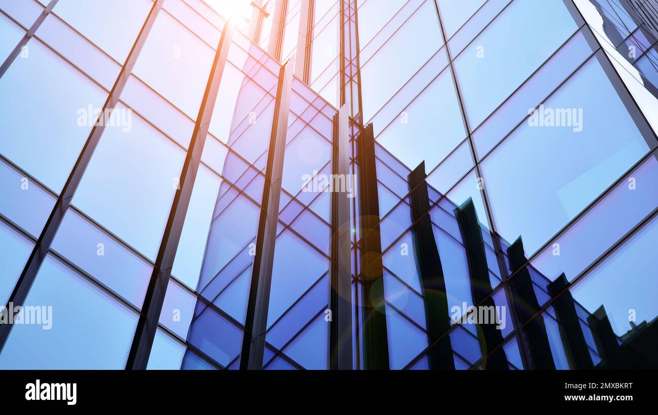 Modern glass facade against blue sky. Bottom view of a building in the ...