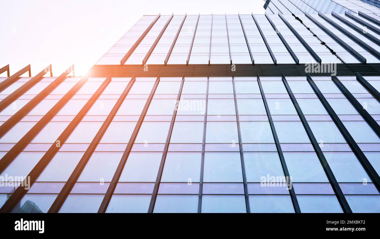 Modern glass facade against blue sky. Bottom view of a building in the ...
