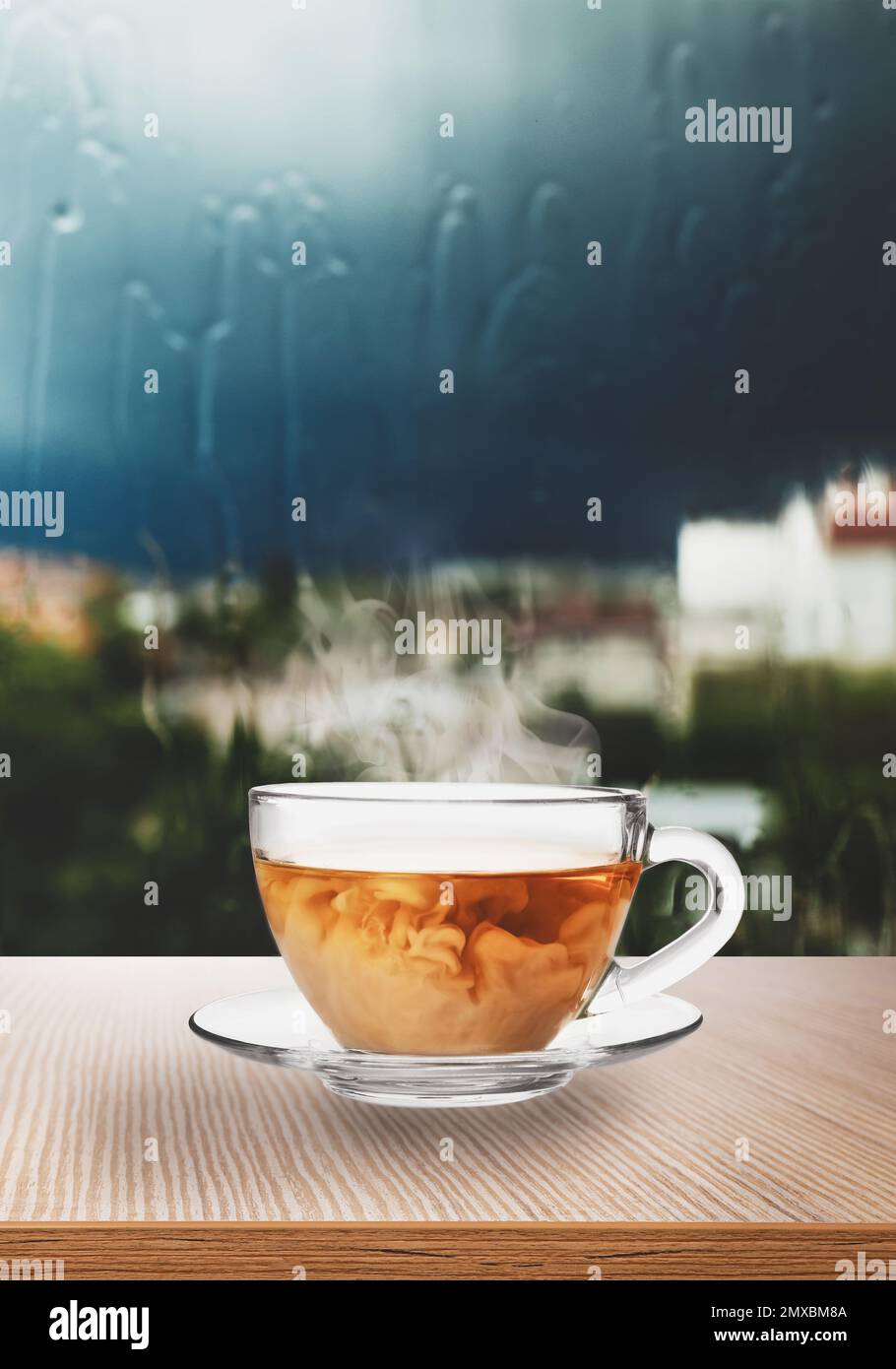 Glass cup with hot black tea and milk near window on rainy day Stock ...