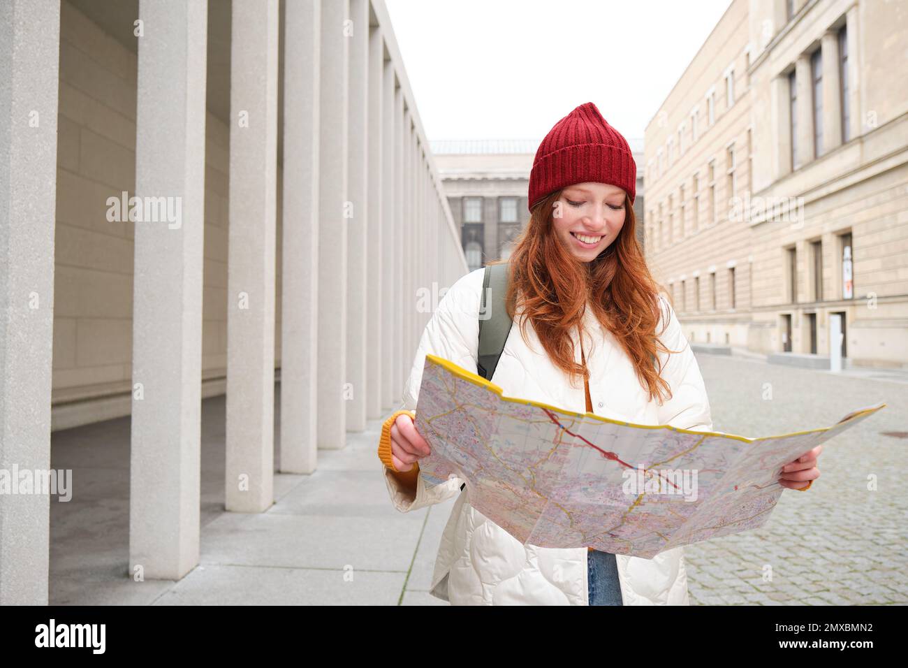 Redhead girl, tourist explores city, looks at paper map to find way for historical landmarks ...