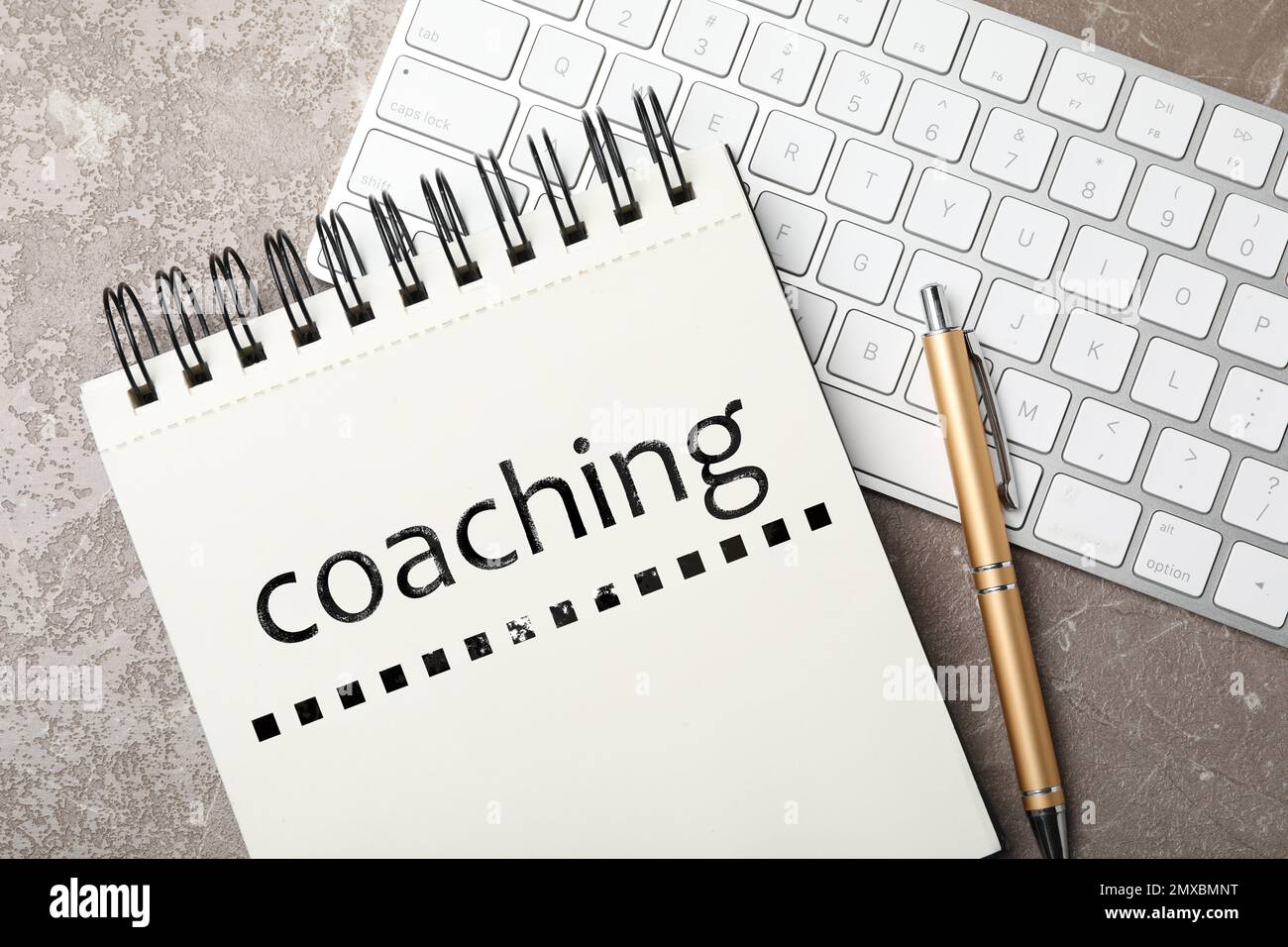 Adult learning. Notebook with word Coaching and keyboard on grey marble ...
