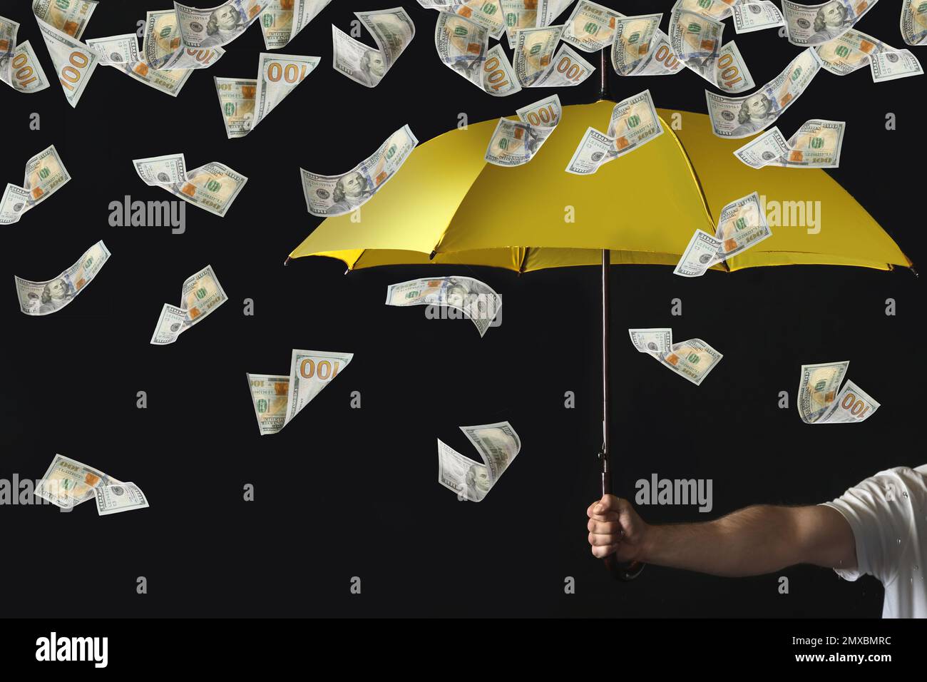 Man holding yellow umbrella under money rain on black background ...