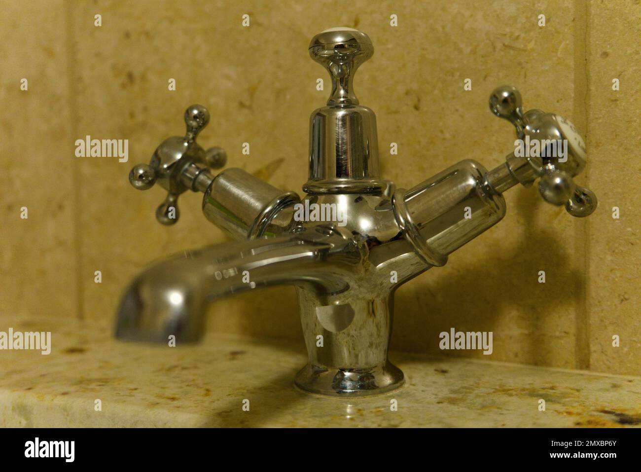 Silver chrome tap in bathroom with marble fossil tiled walls Stock ...