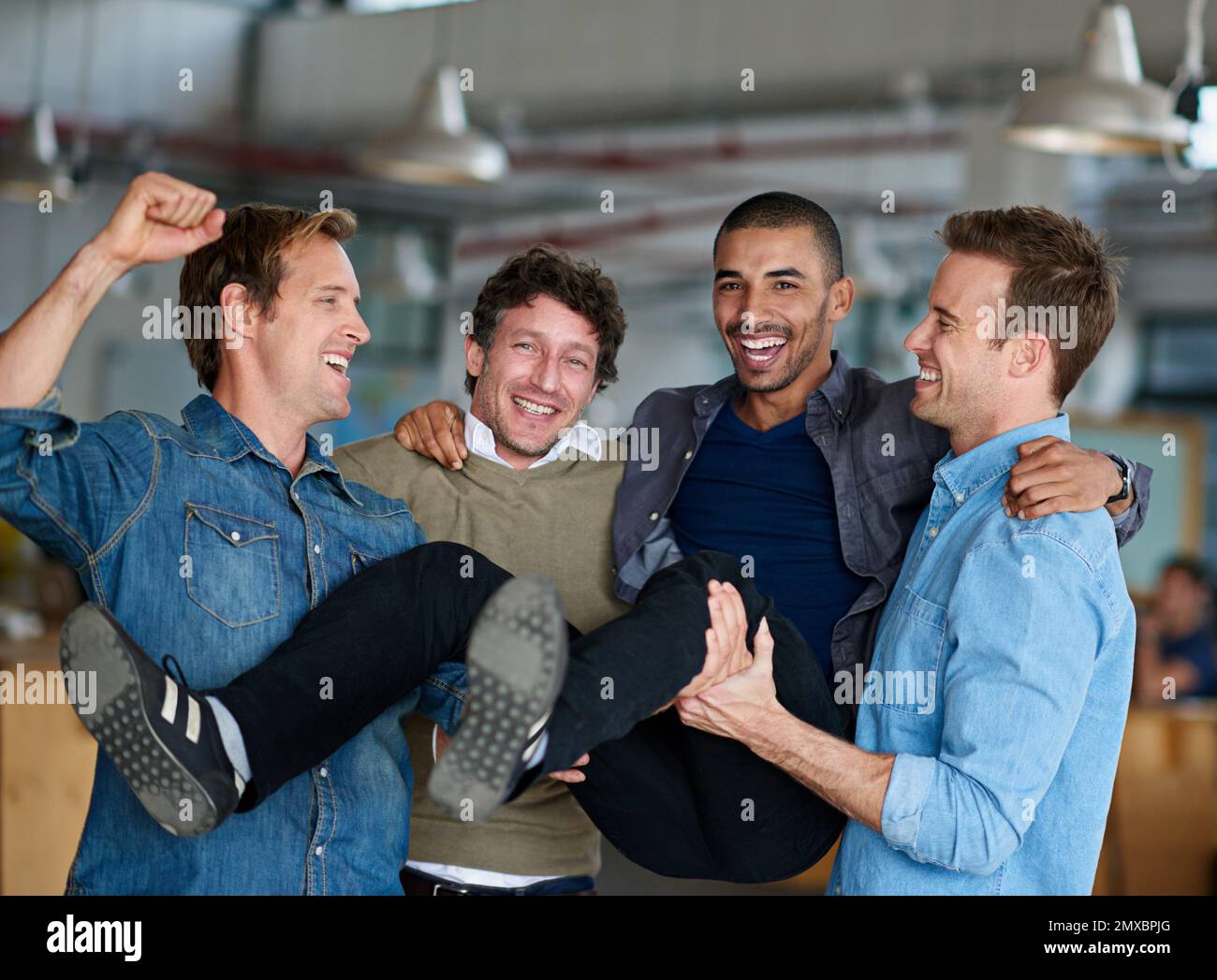 Our office hero. Male colleagues lifting up a coworker in victory and ...