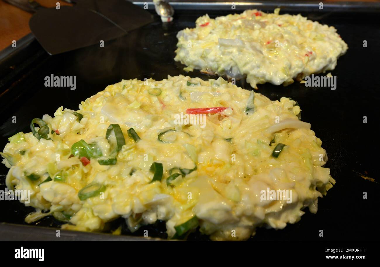 A Japanese woman cooking Okonomiyaki on a teppan Stock Photo - Alamy