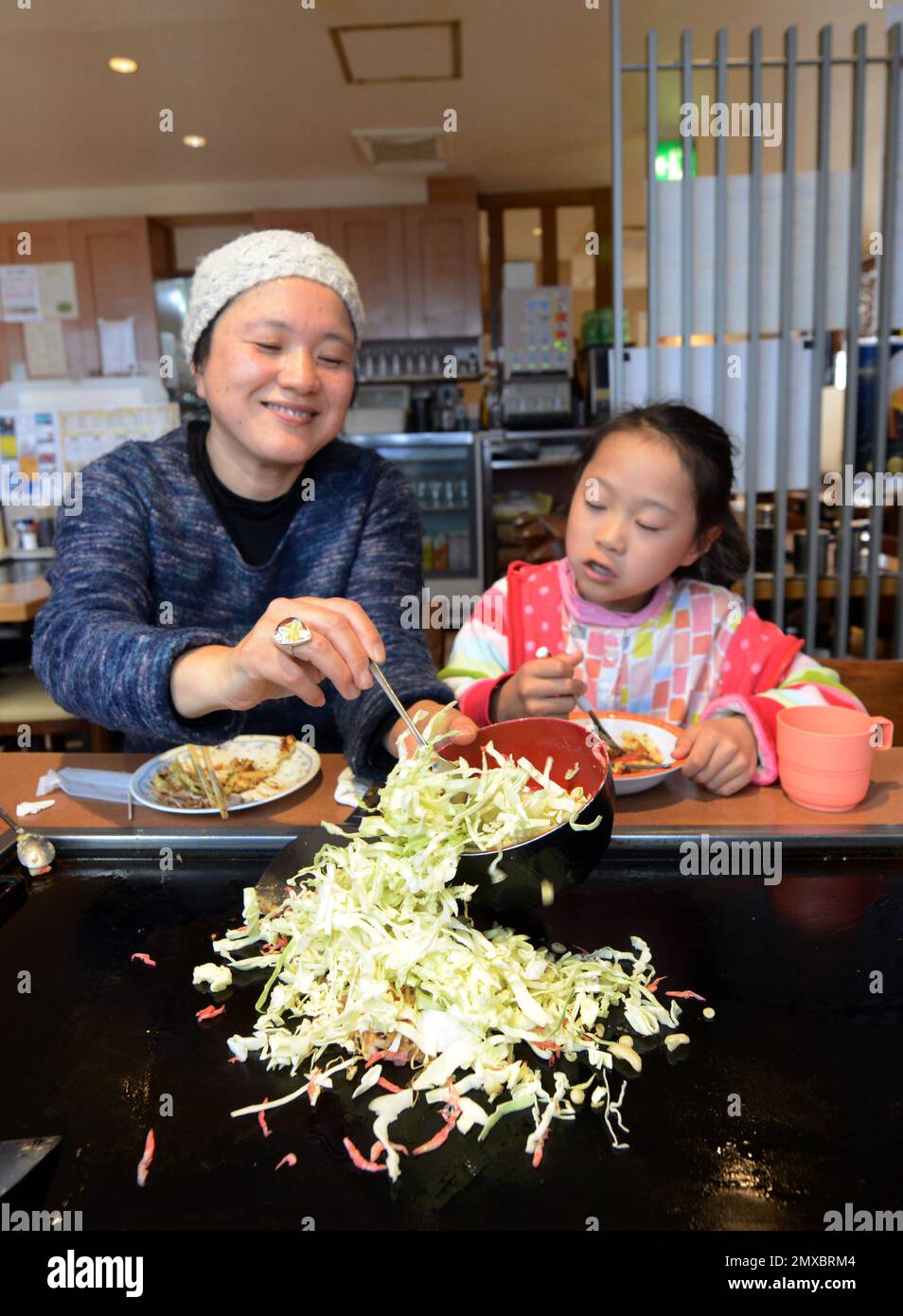 A Japanese woman cooking Okonomiyaki on a teppan Stock Photo - Alamy