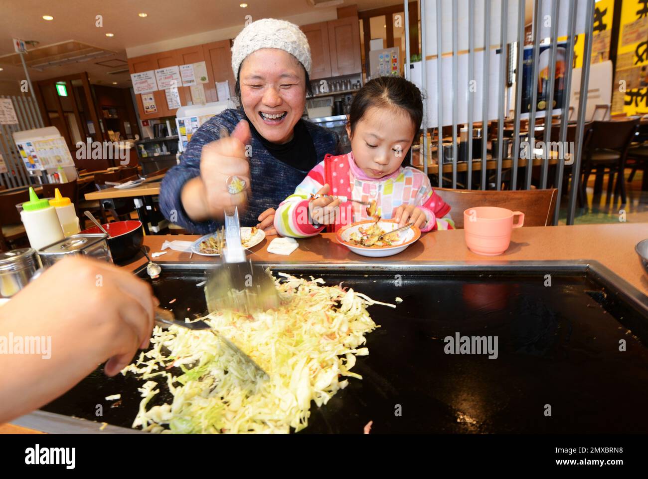 A Japanese woman cooking Okonomiyaki on a teppan in Tokyo, Japan Stock ...