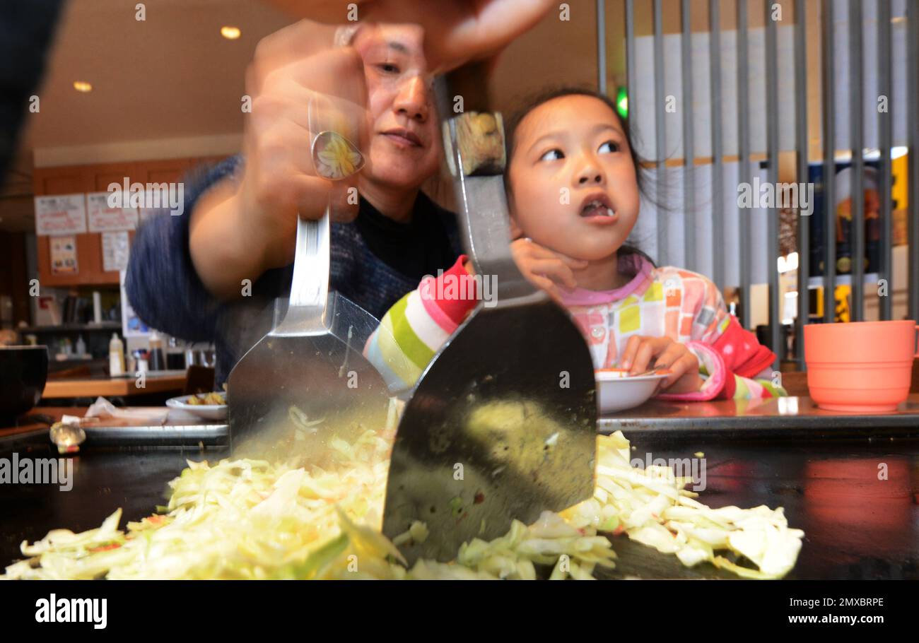 A Japanese woman cooking Okonomiyaki on a teppan Stock Photo - Alamy