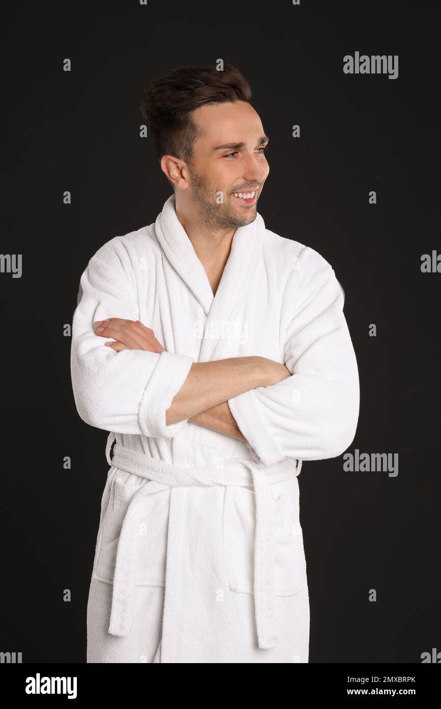Happy young man in bathrobe on black background Stock Photo - Alamy