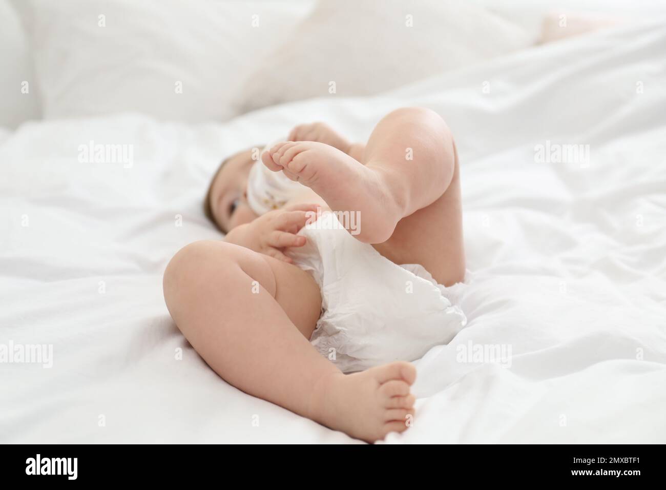 Cute little baby in diaper on bed Stock Photo - Alamy
