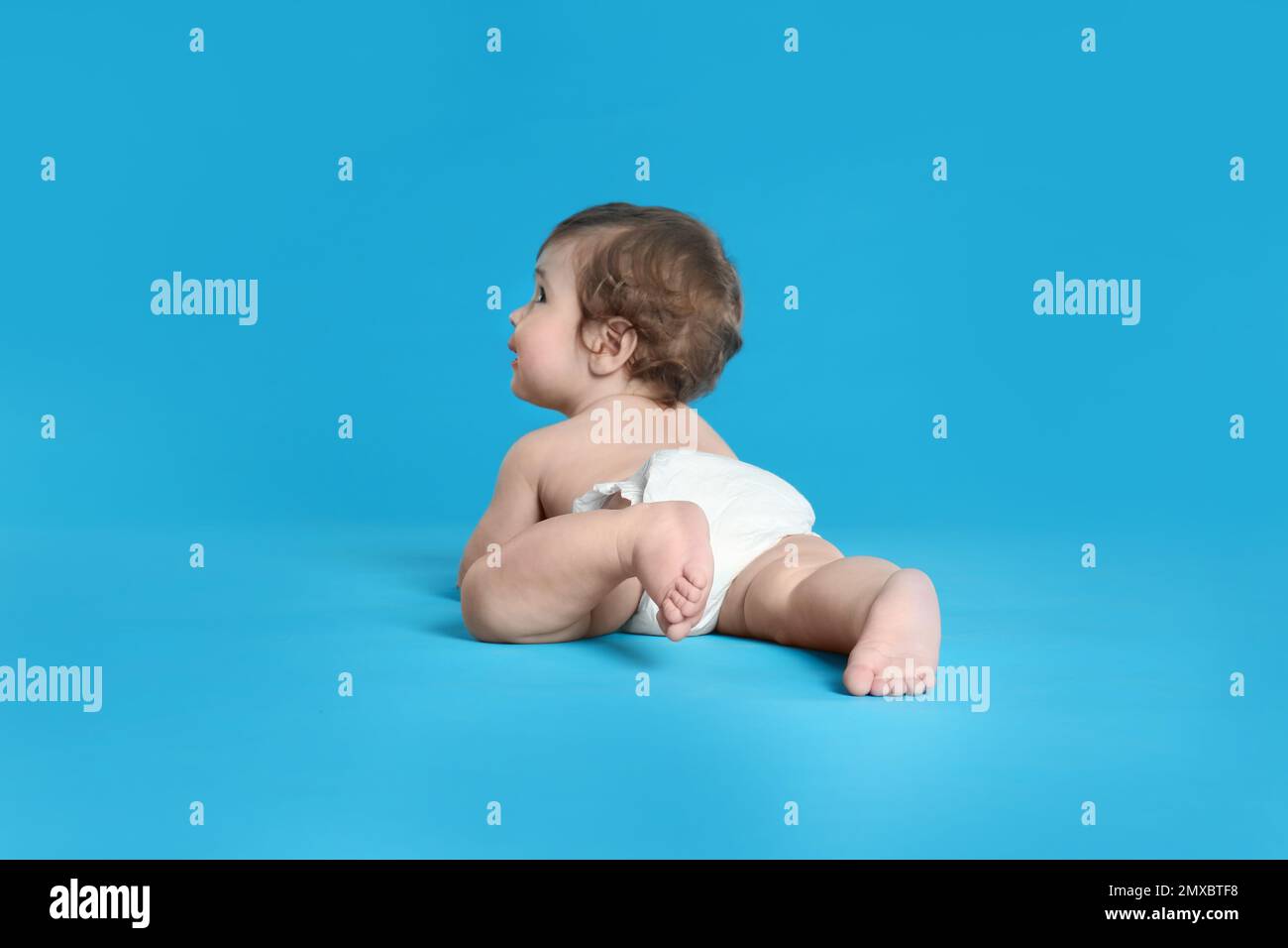 Cute little baby in diaper on light blue background Stock Photo - Alamy