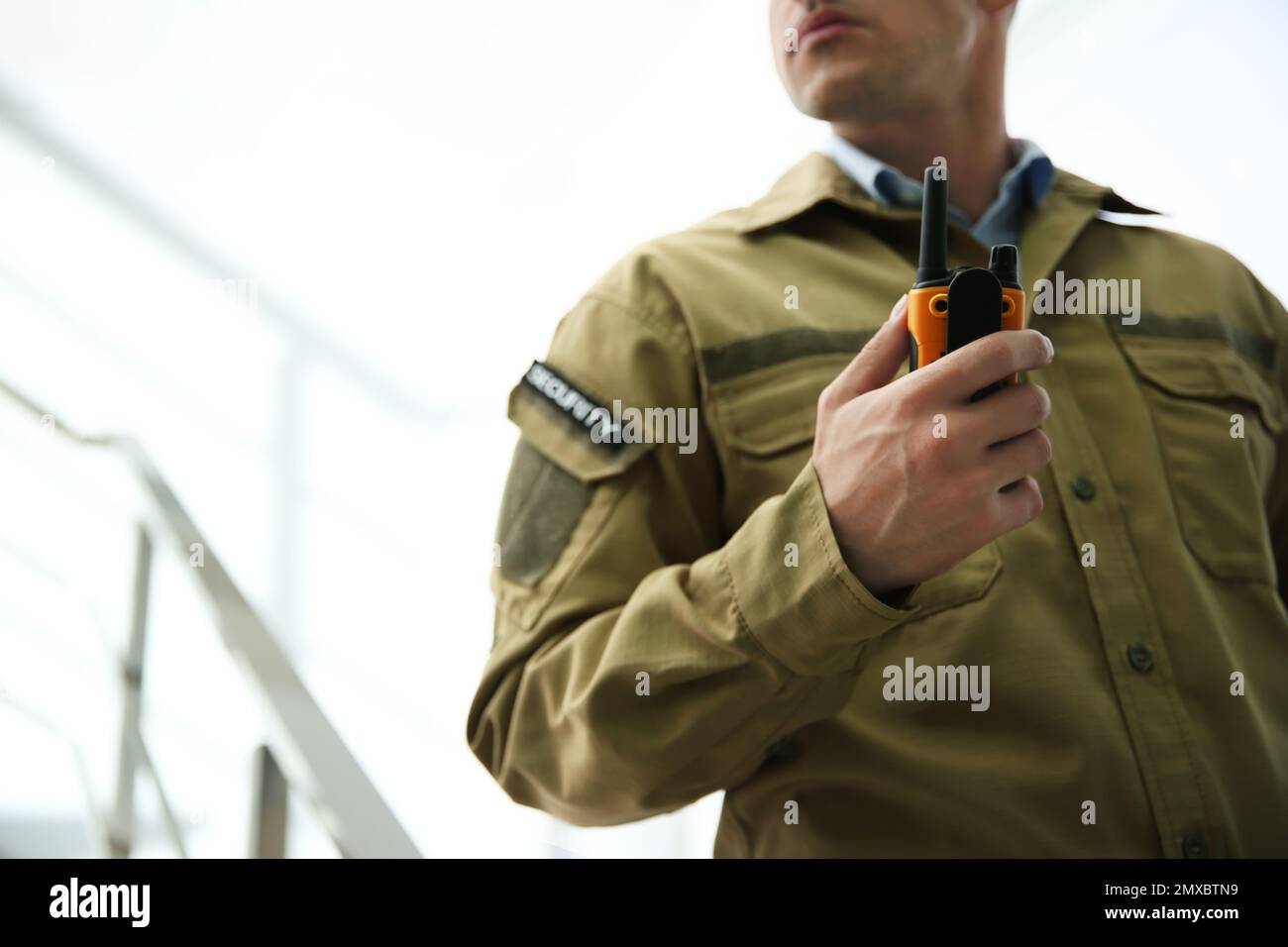 Professional security guard with portable radio set indoors, closeup ...