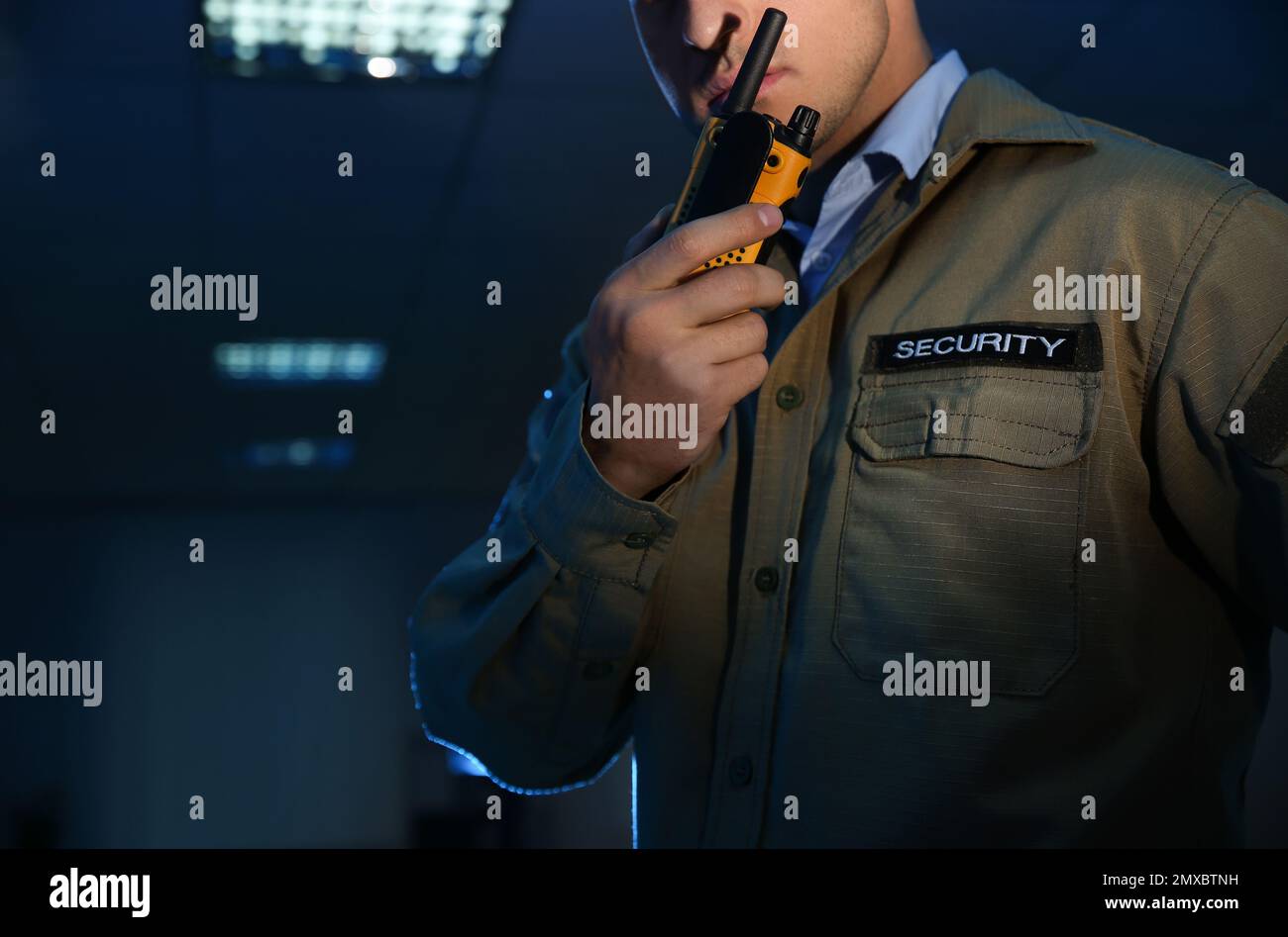 Professional security guard with portable radio set in dark room ...