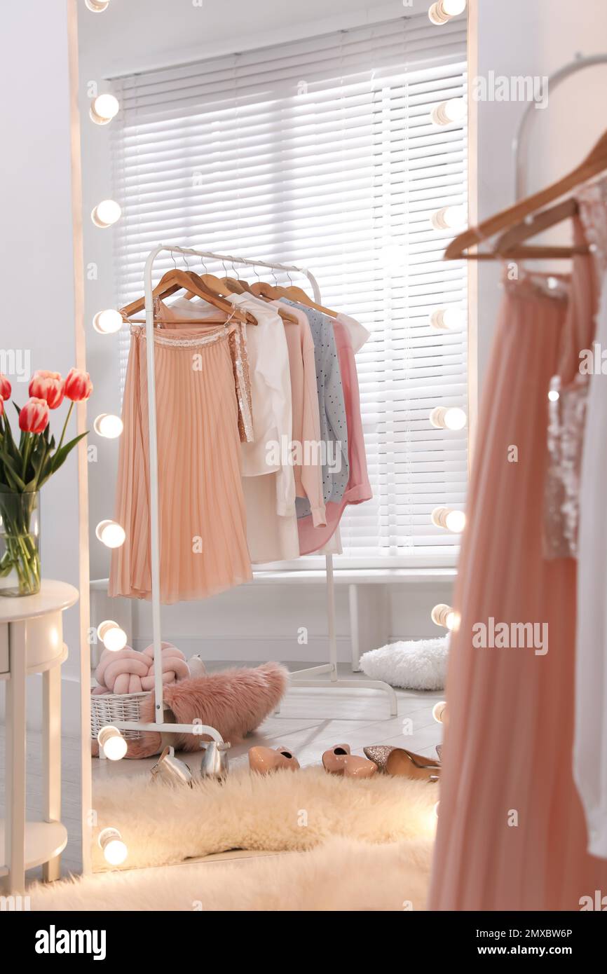 Rack with stylish women's clothes and mirror indoors. Interior design ...