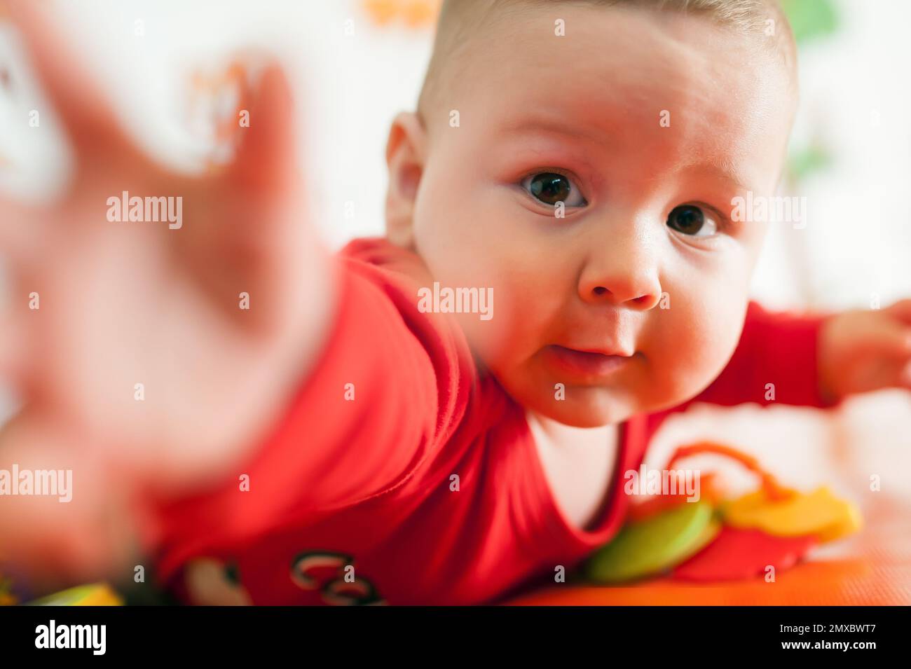 Cute baby boy stretches out his hand towards the camera in front and ...