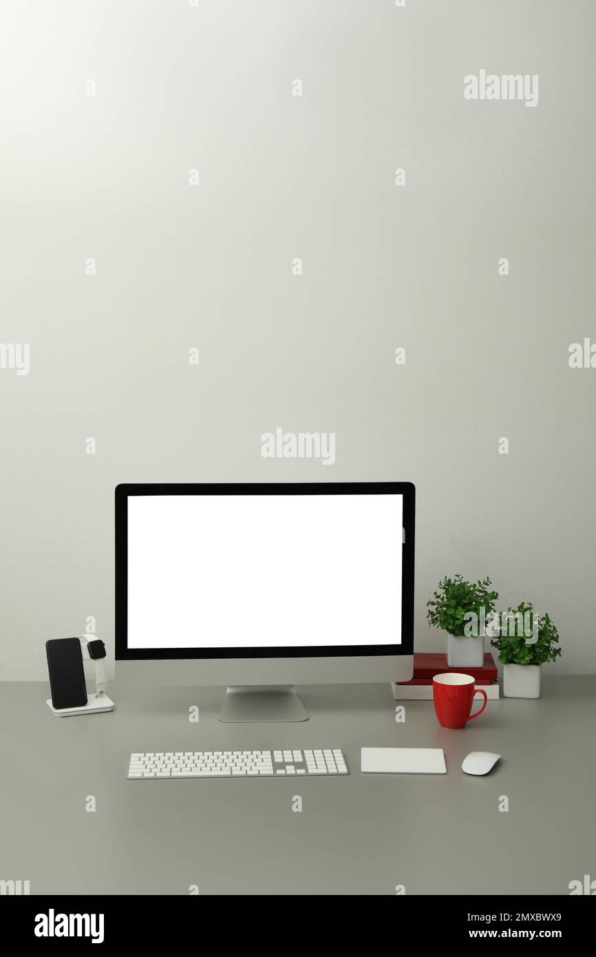 Modern workplace with computer, charging devices and houseplants ...