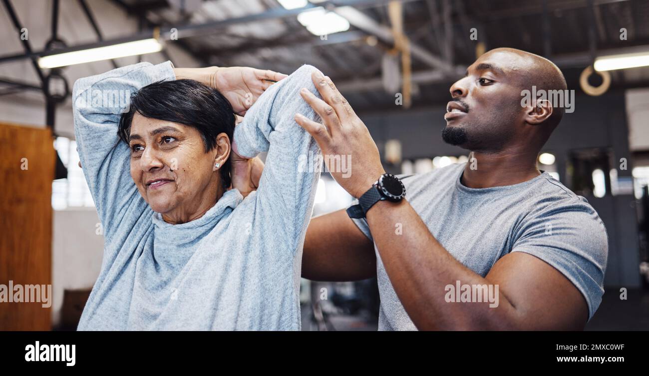 Coach, personal trainer and senior woman stretching arms in gym with ...