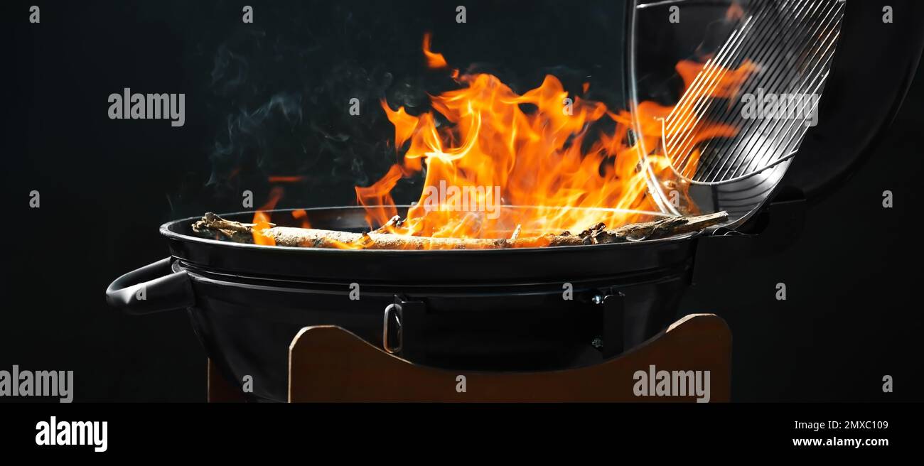 New modern barbecue grill with burning firewood on dark background ...