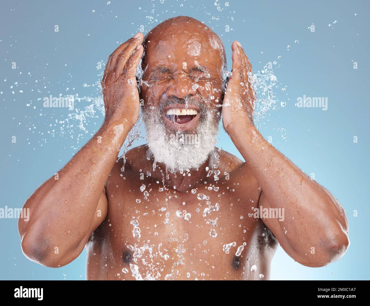 Water splash, beauty and black man isolated on blue background for face cleaning, beauty and ...