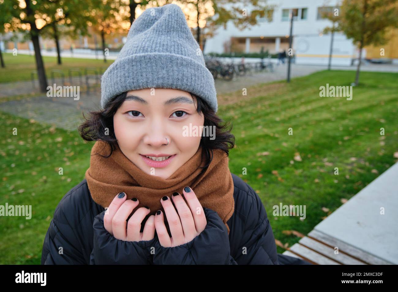Portrait of cute asian girl in hat and scarf, walks around town in ...