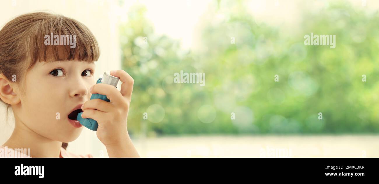 Little girl using asthma inhaler on blurred background, space for text ...