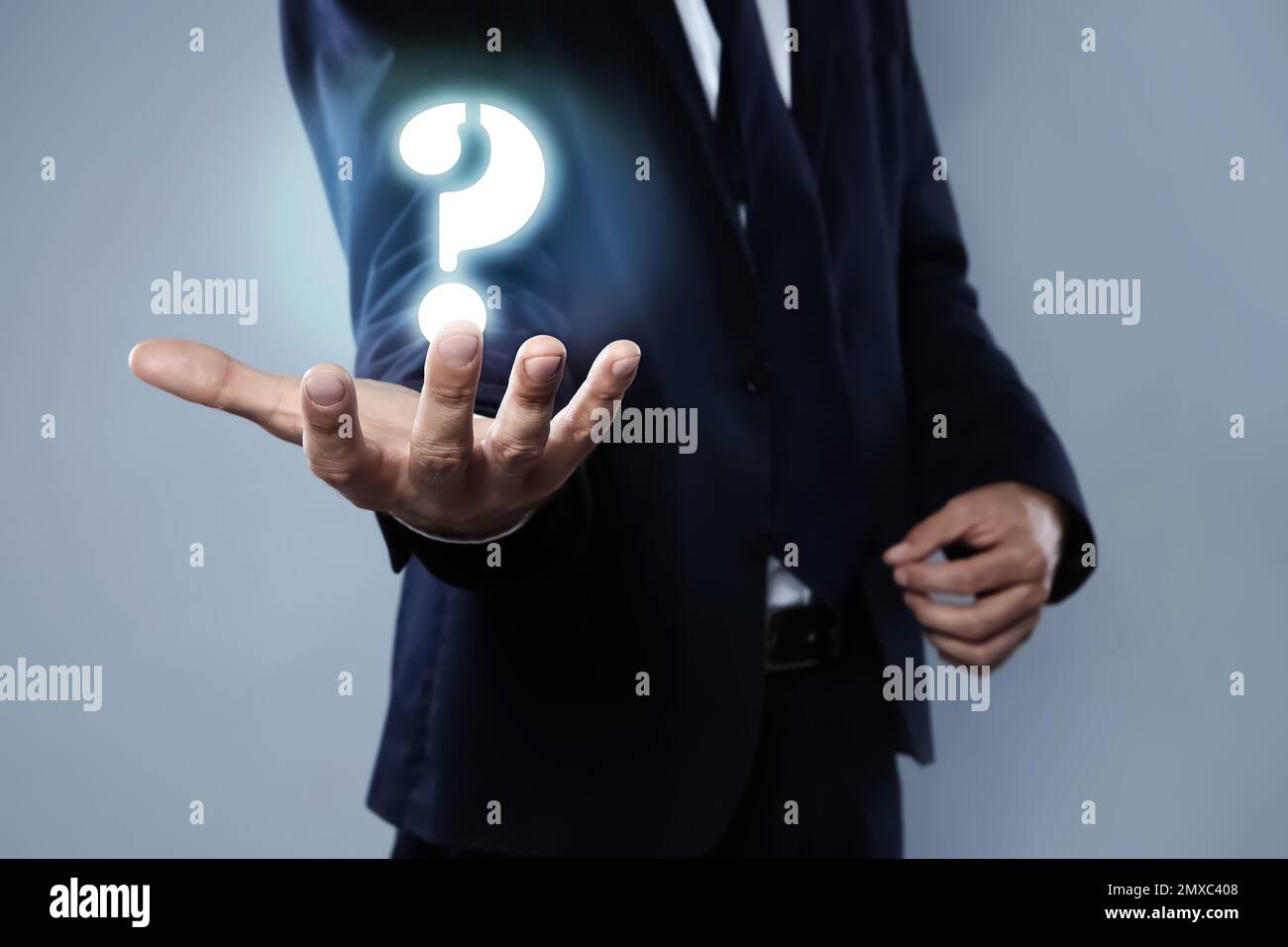 Businessman demonstrating question mark symbol on grey background ...