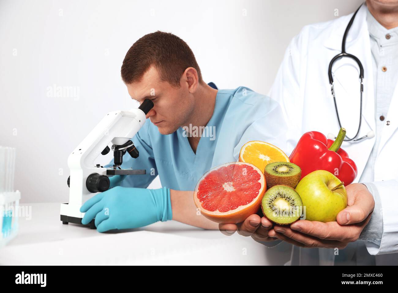 Scientist with microscope at table and his colleague in laboratory ...