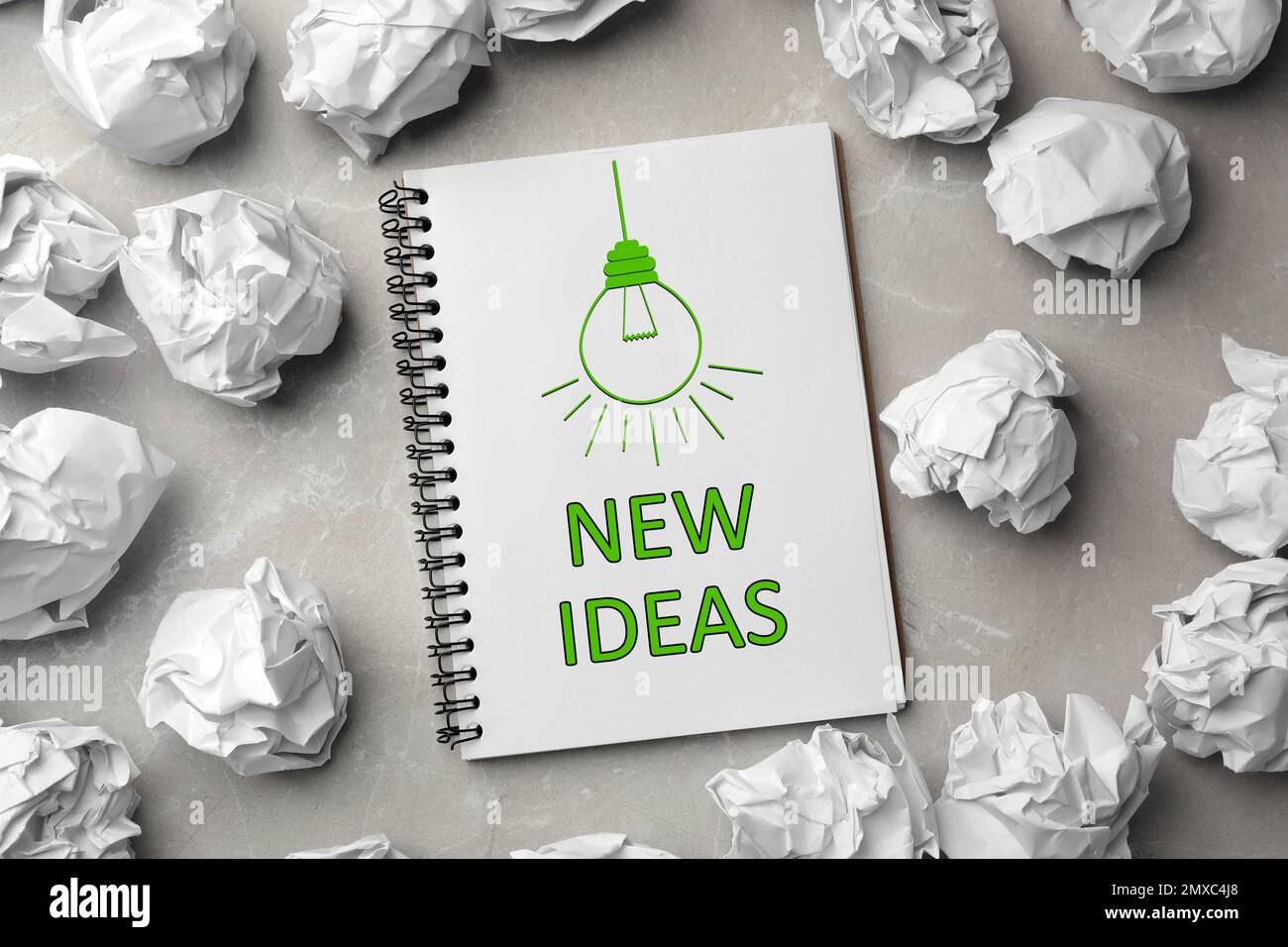 Notebook with words NEW IDEAS and crumpled paper on grey marble table ...