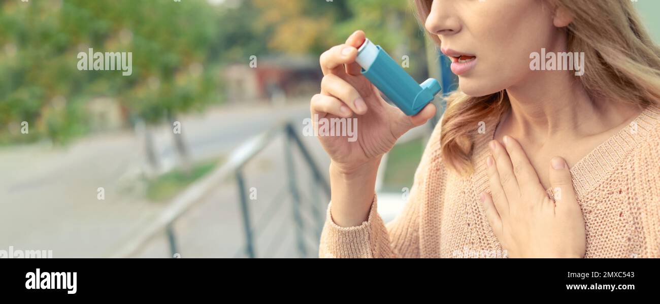 Closeup view of woman using asthma inhaler outdoors, space for text ...