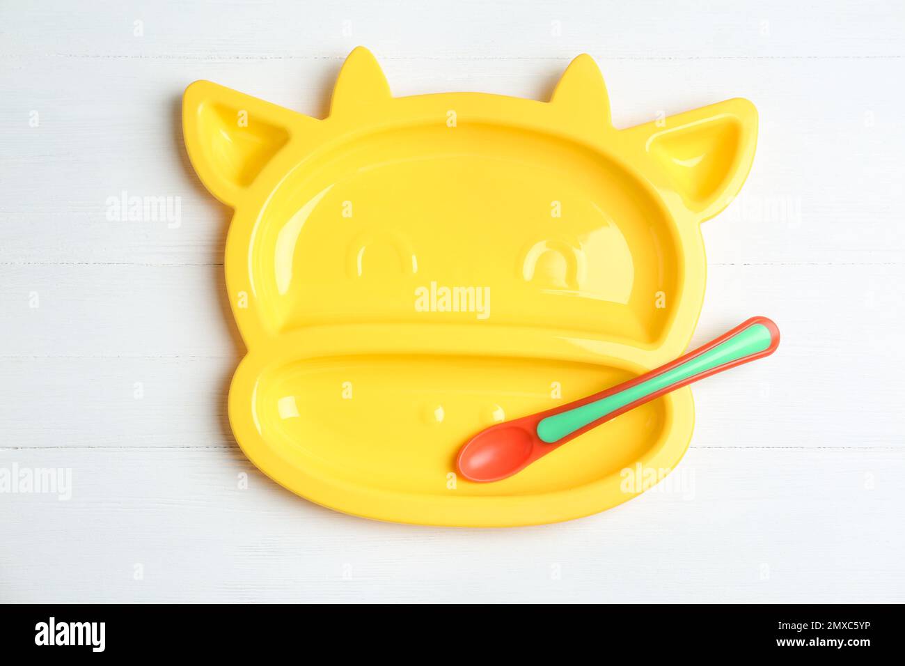 Cute animal shaped plate and spoon on white wooden table, top view ...
