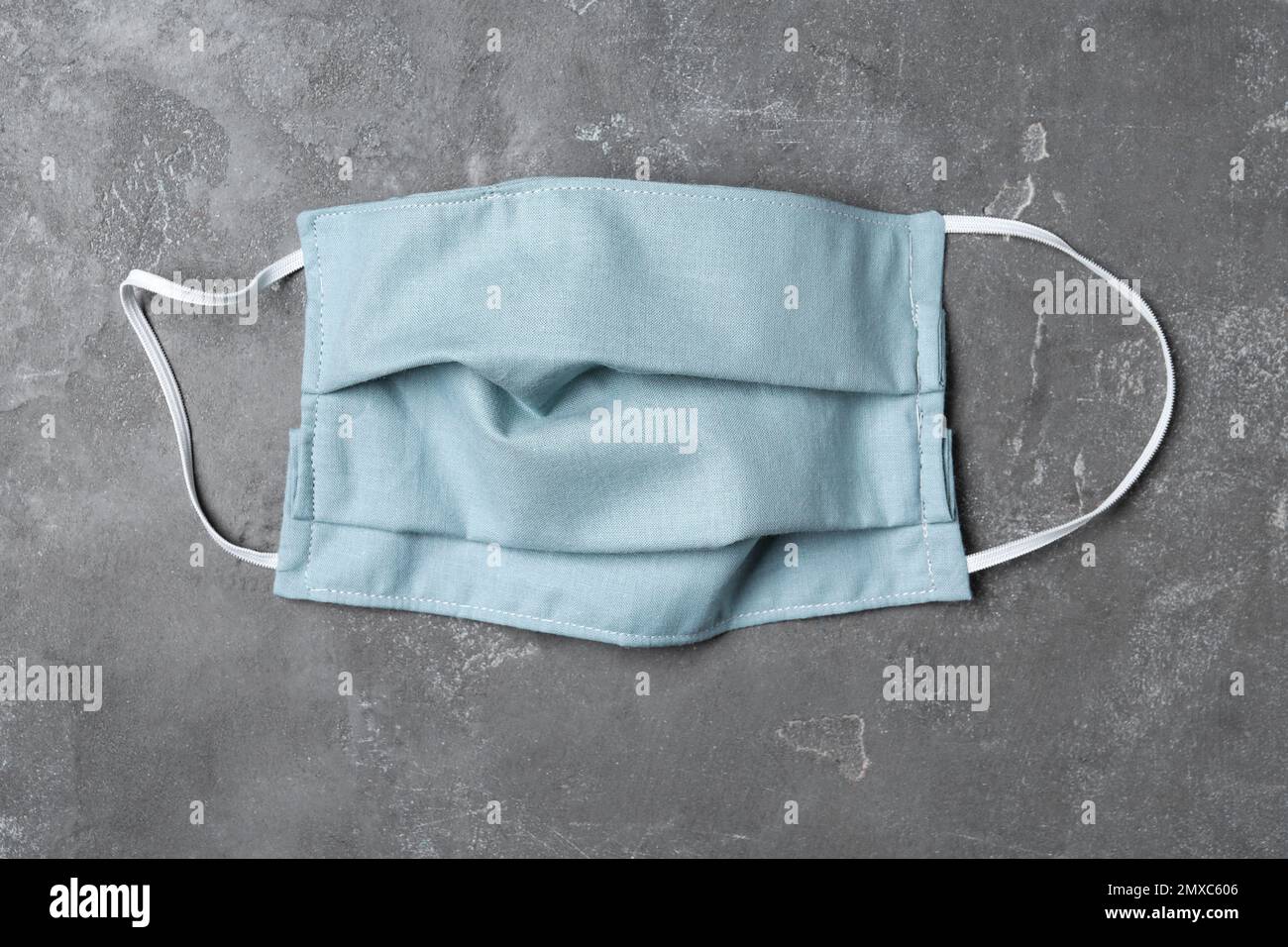 Homemade protective mask on grey stone background, top view. Sewing ...