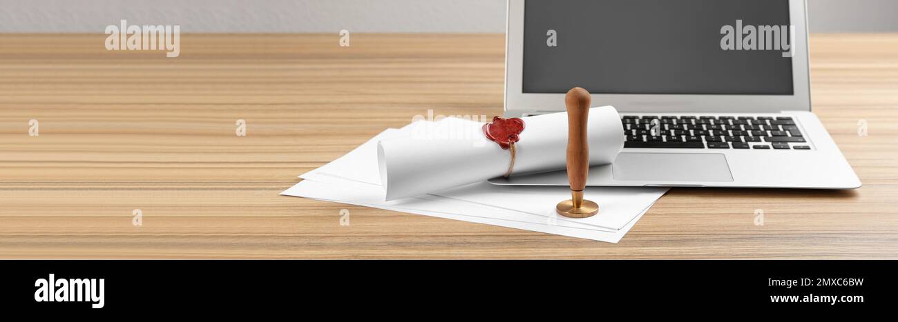 Notary's public pen and sealed document near laptop on wooden table ...
