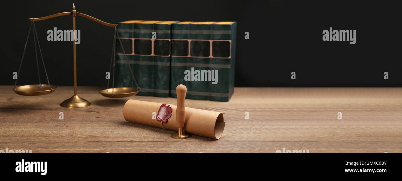 Notary's public pen, sealed document and scales on wooden table against ...