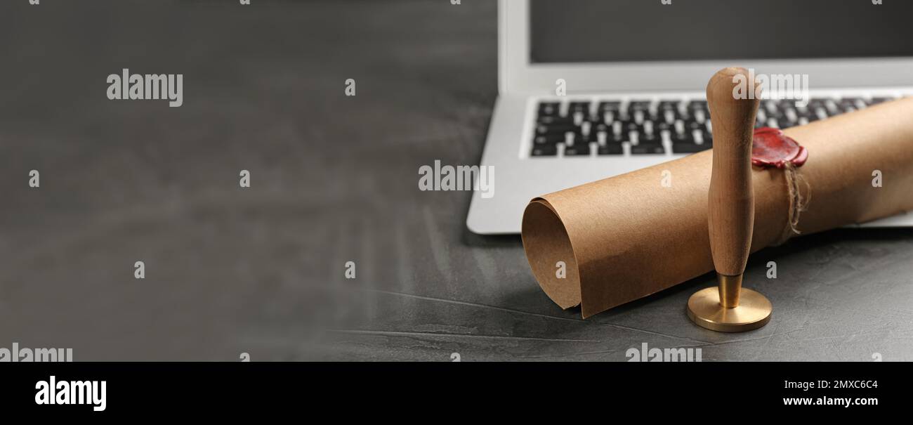 Notary's public pen and sealed document near laptop on grey stone table ...