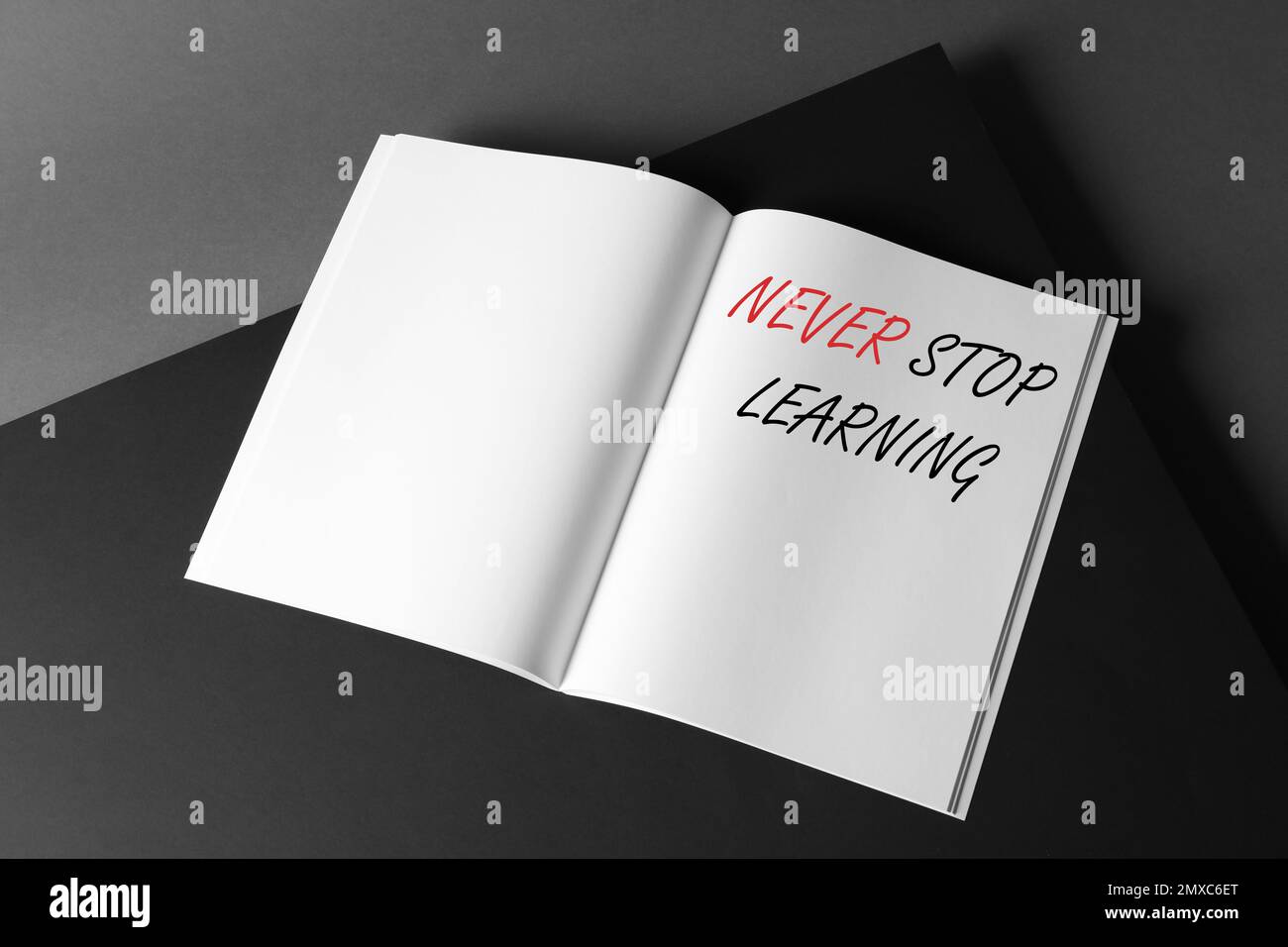 Open book with phrase NEVER STOP LEARNING on dark background, above ...