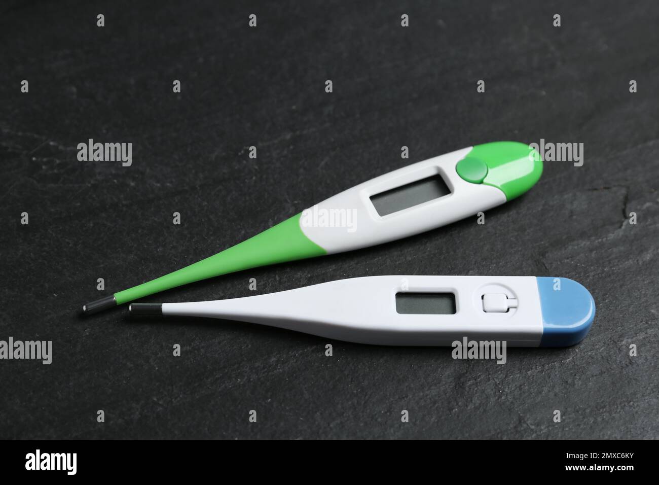 Modern digital thermometers on black slate background Stock Photo - Alamy