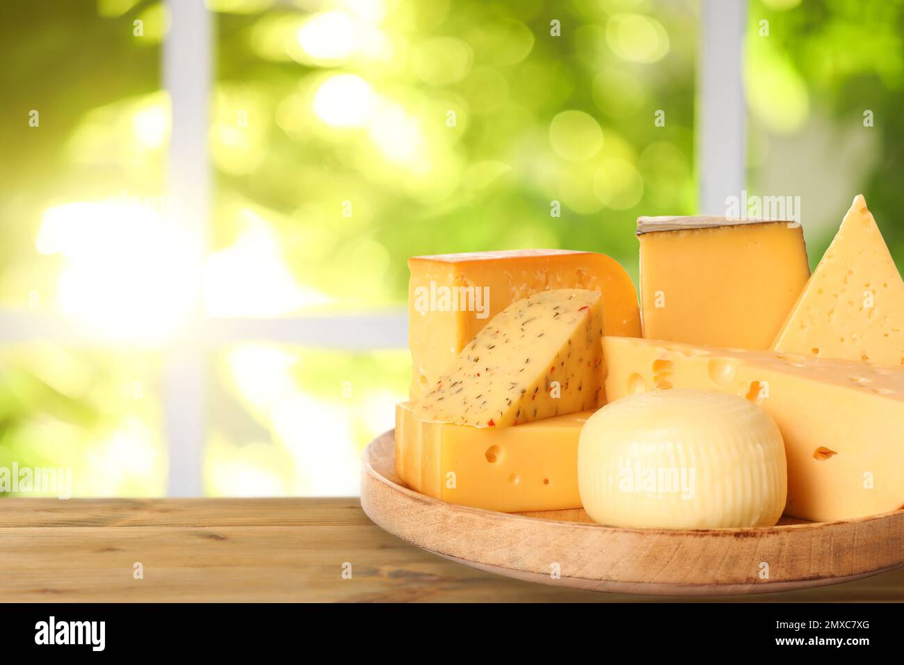 Different types of delicious cheeses on wooden table outdoors, space ...