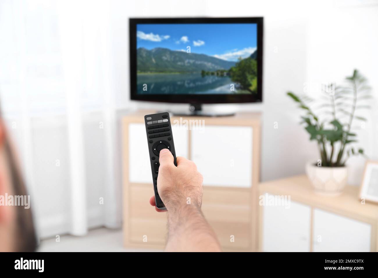 Man switching channels on modern TV with remote control at home Stock Photo - Alamy